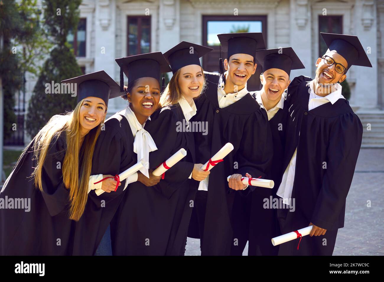 Laughing excited group of multicultural people in graduation gowns and ...