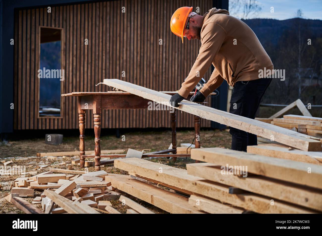 Man worker building wooden frame house. Carpenter using angle for ...