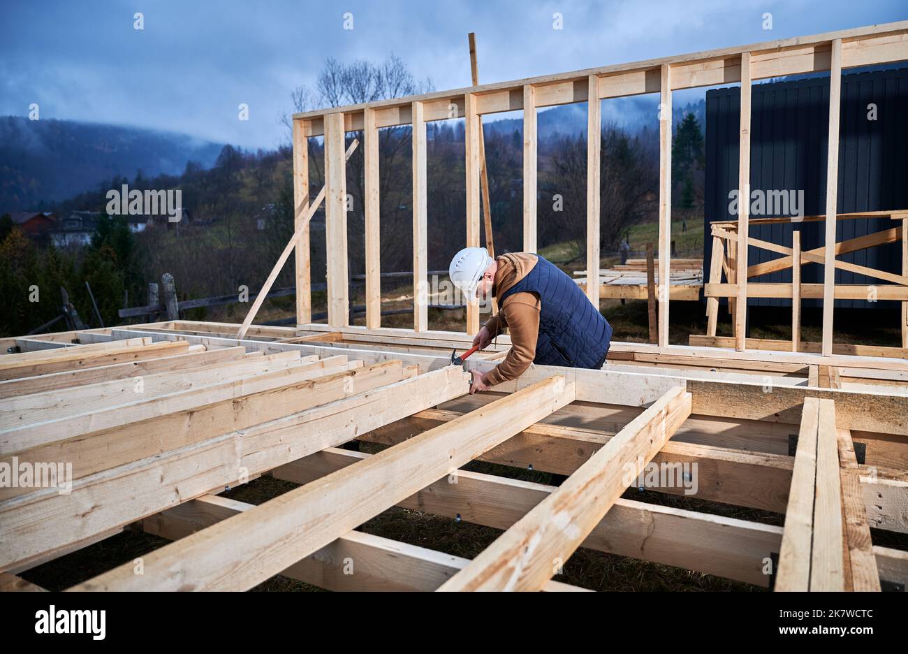 Man worker building wooden frame house on pile foundation. Carpenter ...