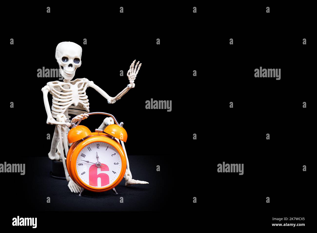 A human skeleton waving his hand, greeting holding an orange alarm ...