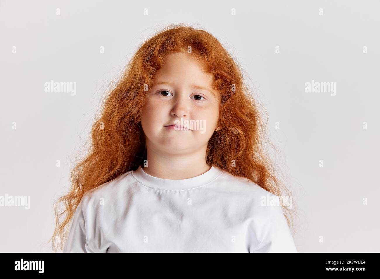 Cute little girl, kid with long curly red hair looking at camera ...