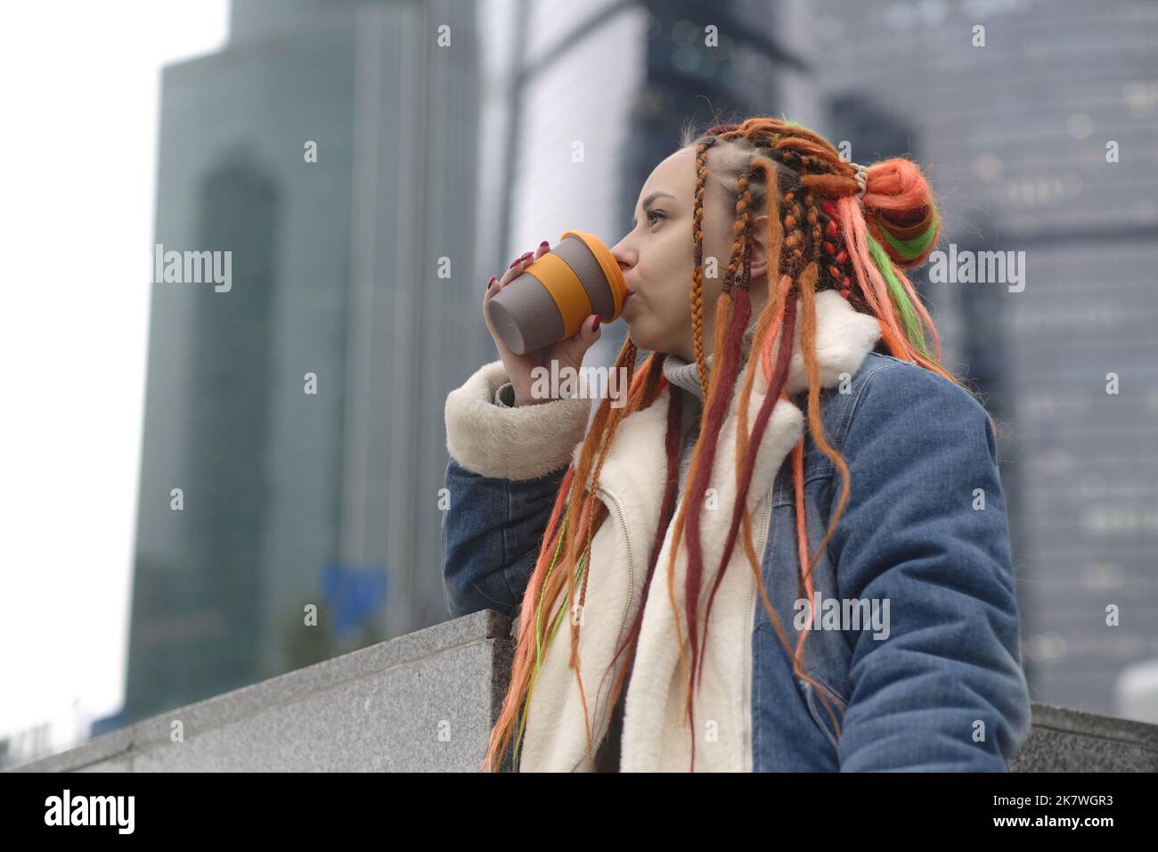 Young woman with dreadlocks drinking coffee from cup, standing in ...