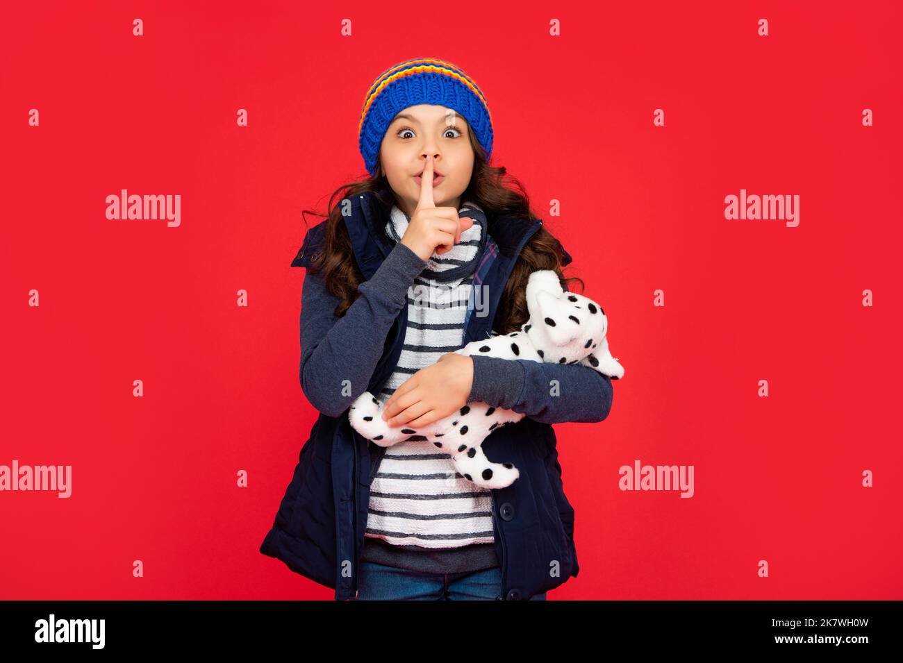 child in puffer jacket hold toy. teen girl on red background. happy ...