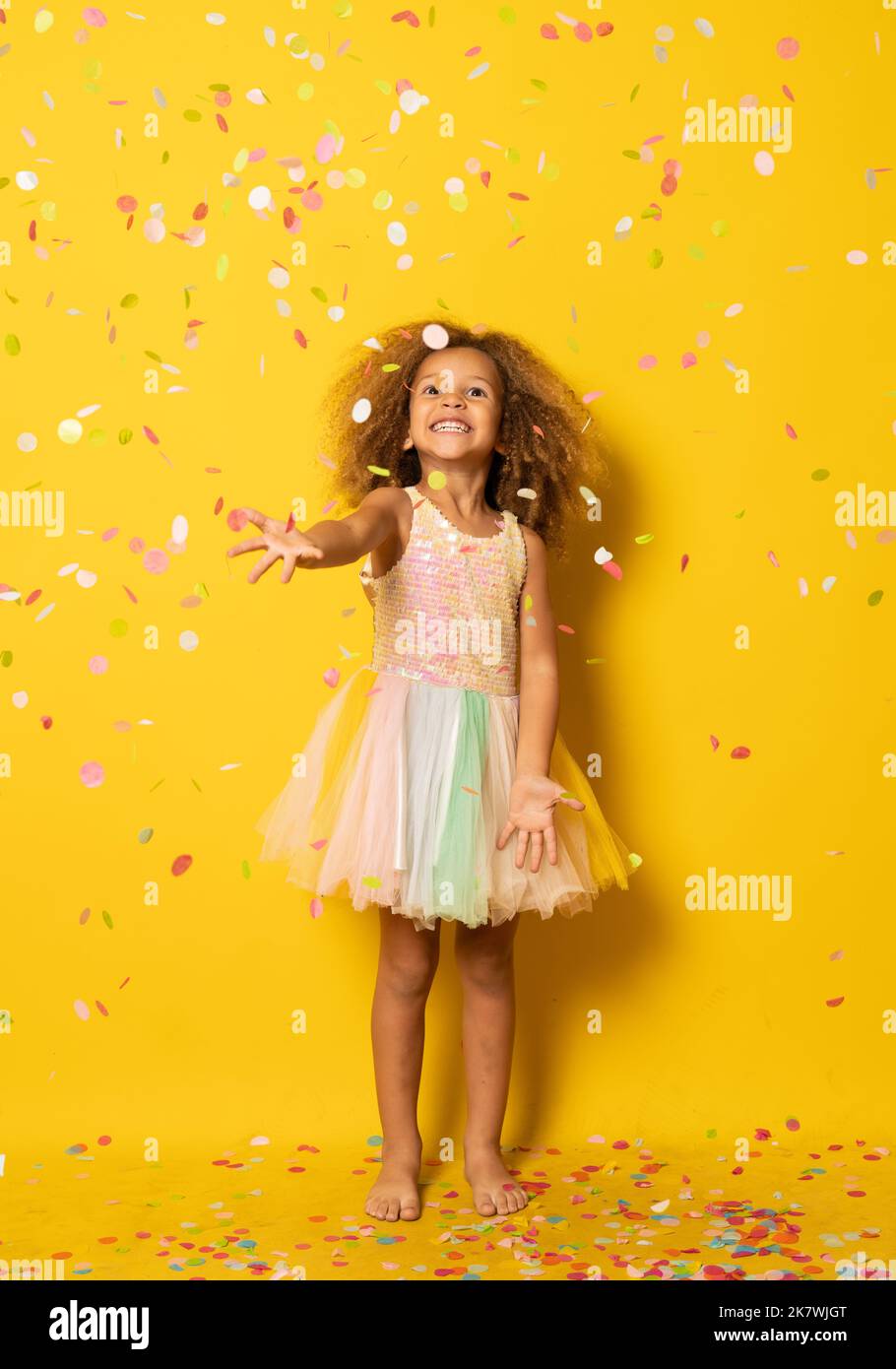 Funny little girl dressed for party in sequins and tutu blowing ...