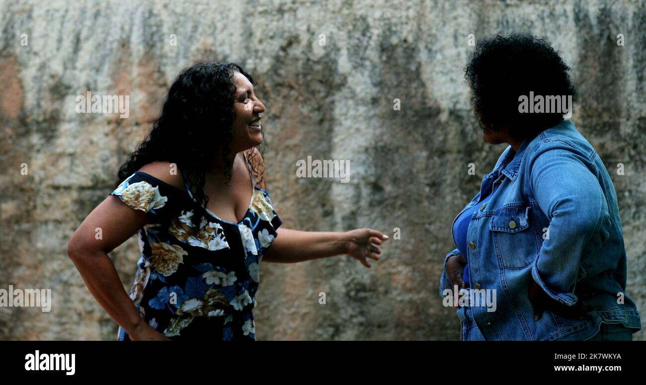 Two latina women speaking in conversation, candid real people gossiping ...