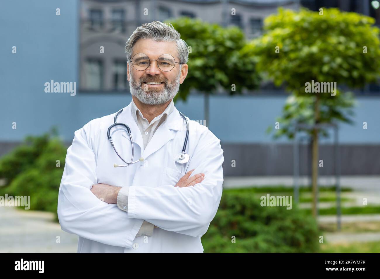 Portrait of senior gray-haired doctor, mature man in white medical coat ...