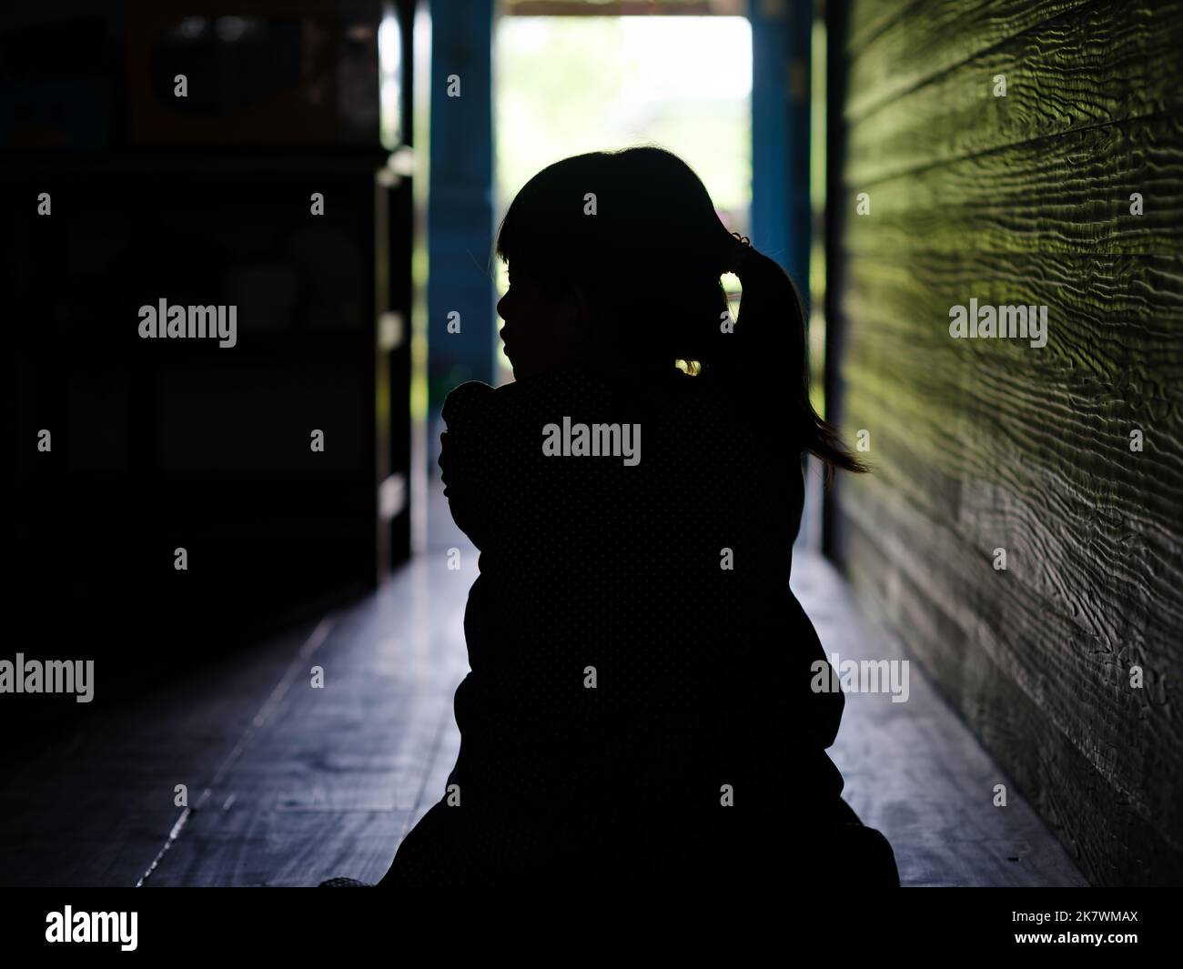 Sad lonely little girl crying while sitting on the floor in dark room ...