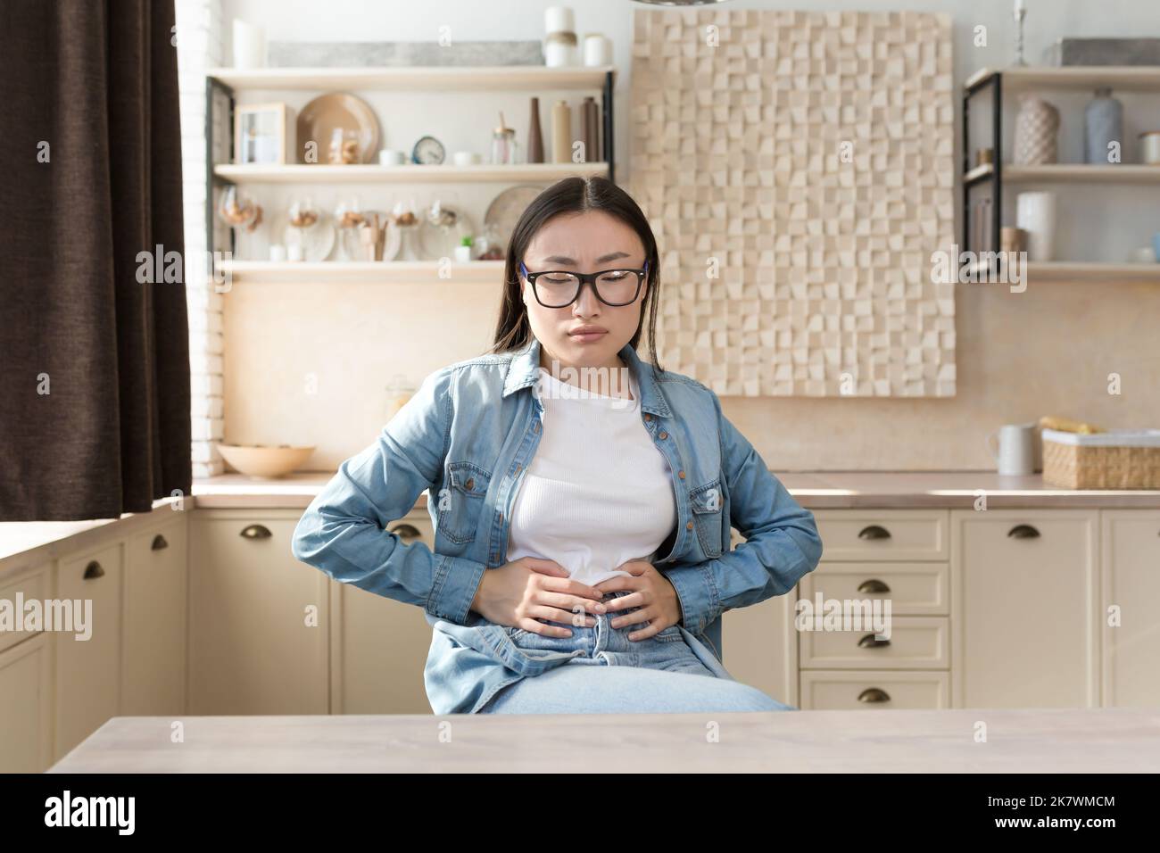 Young woman sick alone at home having severe stomach pain, asian woman ...