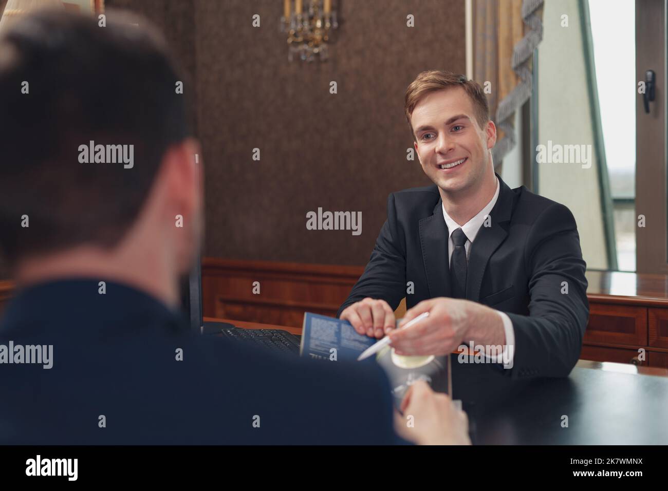 Smiling hotel receptionist helping Businessman to check in and receive ...