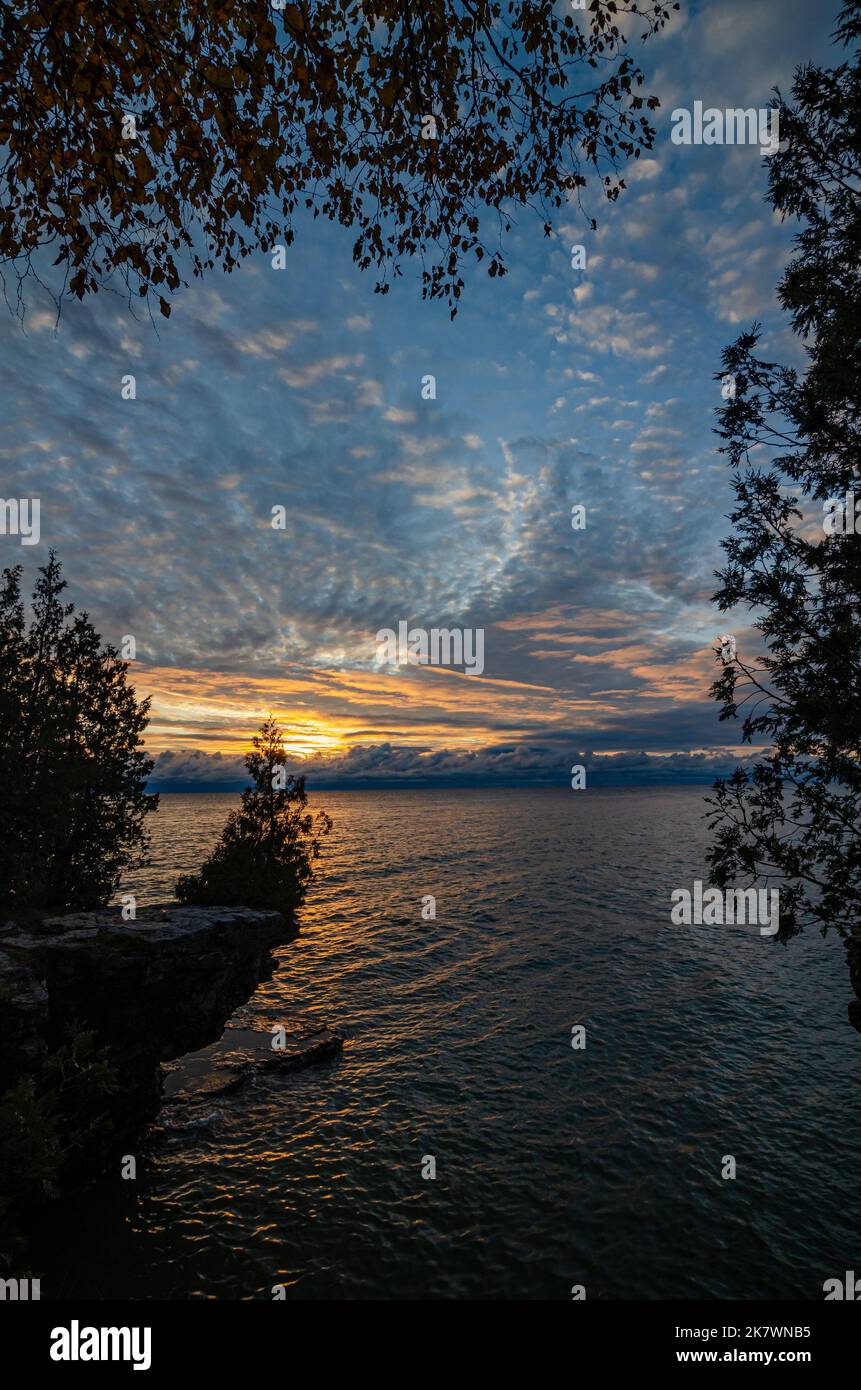 The sun rises over Lake Michigan seen through the surrounding trees on ...