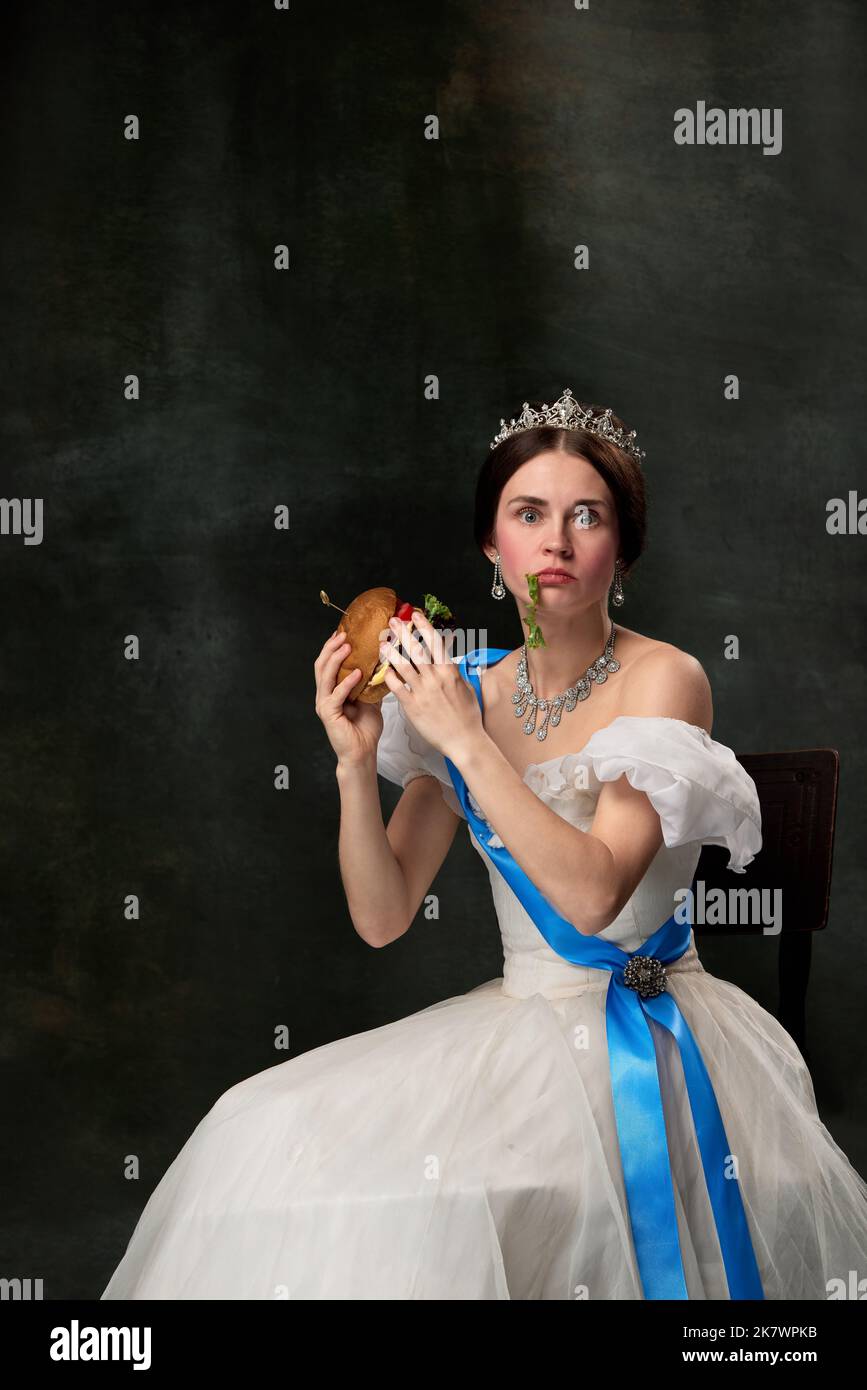 Fast food or dieting. Young funny girl like queen or princess in white ...