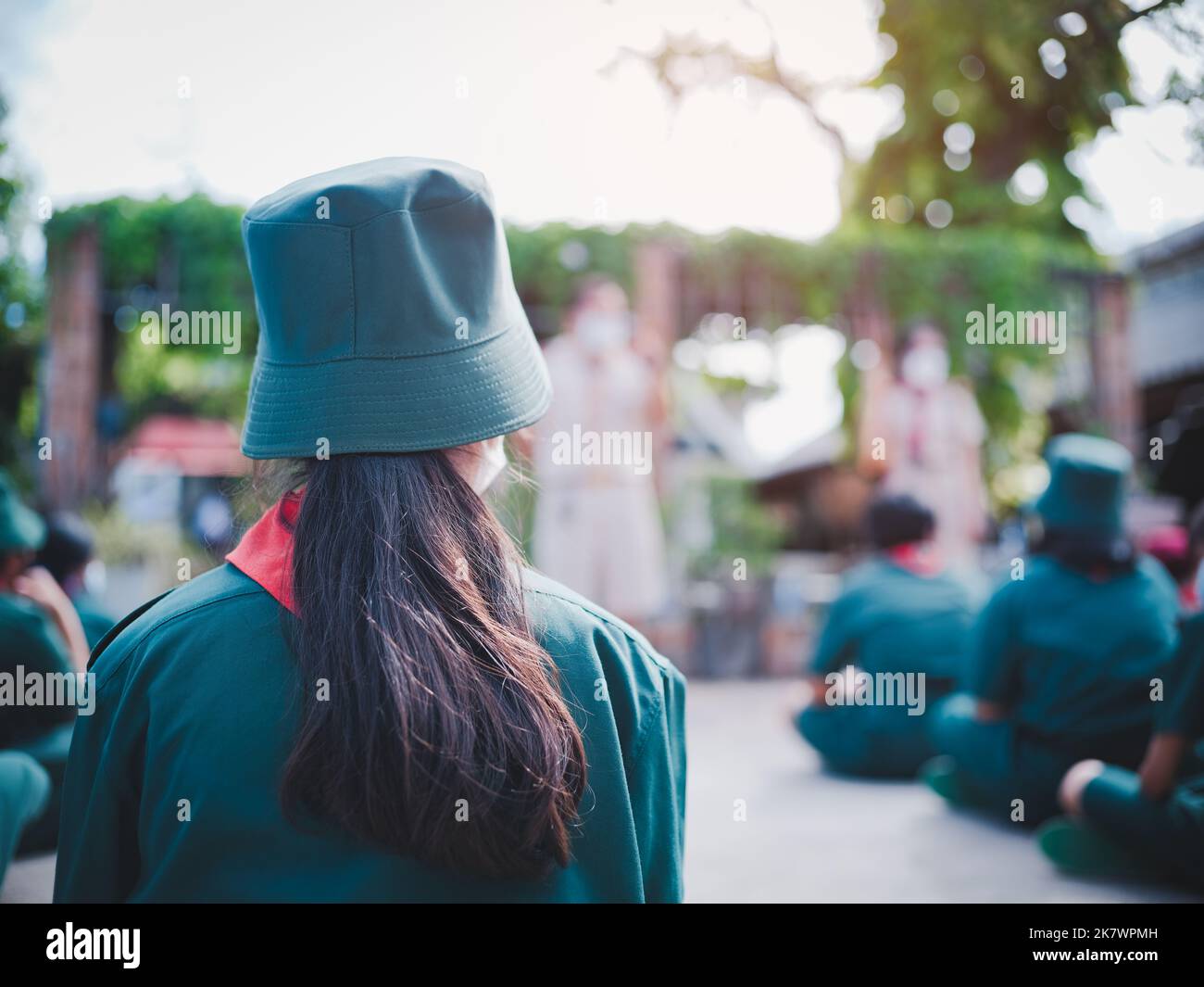 Girl scout in uniform is listening to her teacher with wear face mask ...