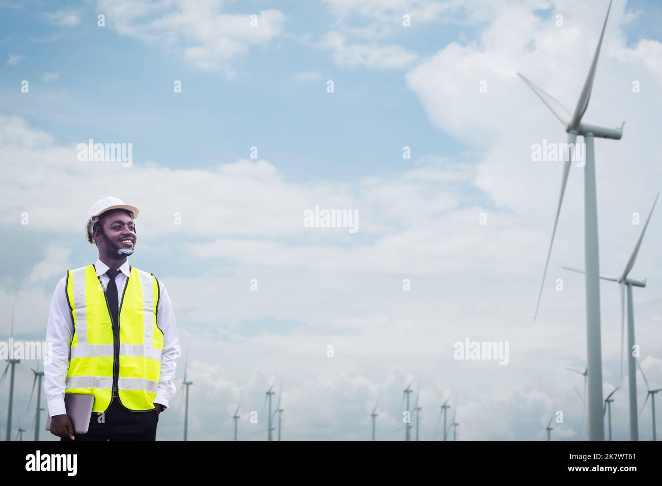 African engineer manager stand holding tablet front the wind turbines ...