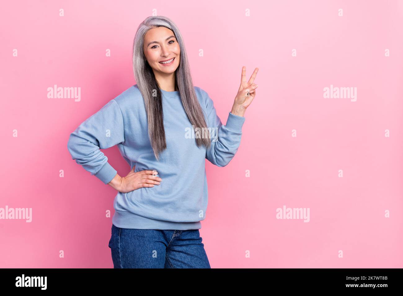 Photo of pretty cute retired woman blue sweater showing v-sign empty ...