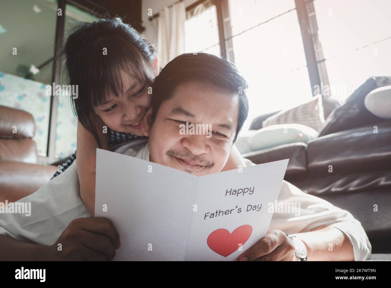 Father was laying down and reading the postcard that his daughter happily gave inside the house ...