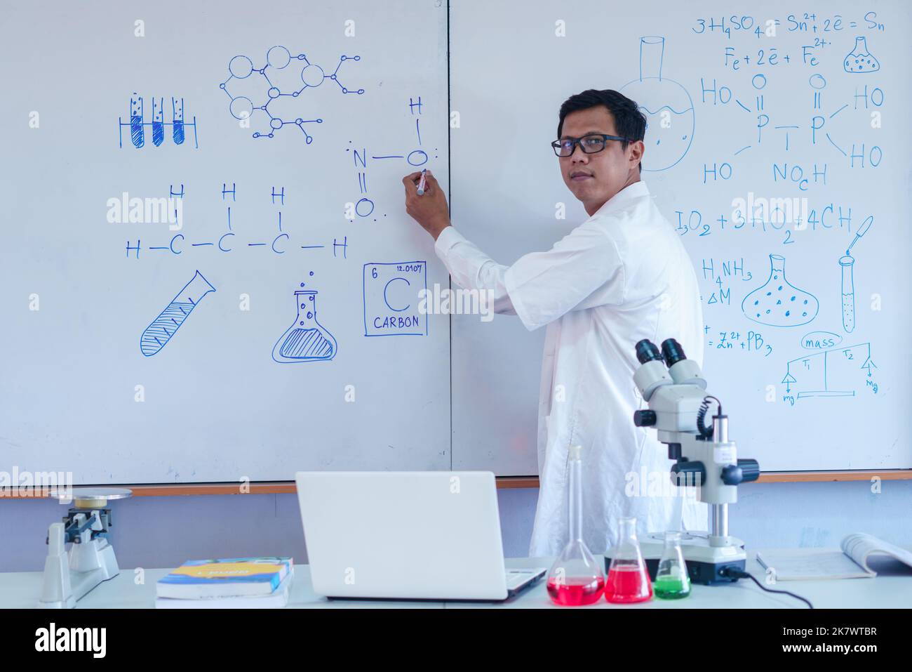 Science teacher writing on blackboard in classroom Stock Photo - Alamy