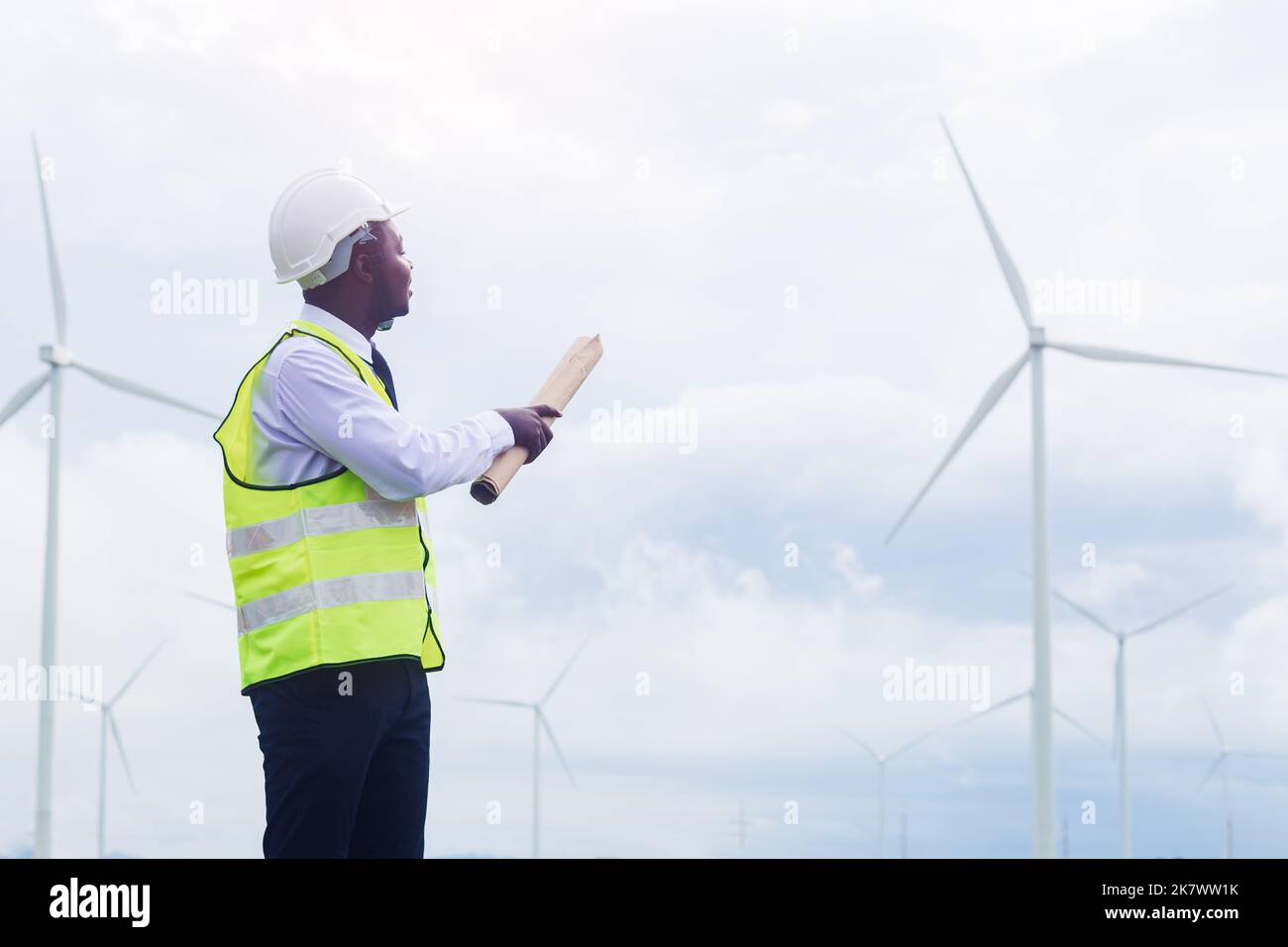 African engineer man stands front the wind turbines generating ...