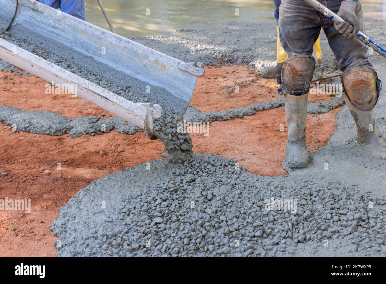 Concrete contractor pours wet concrete during the paving driveway while ...