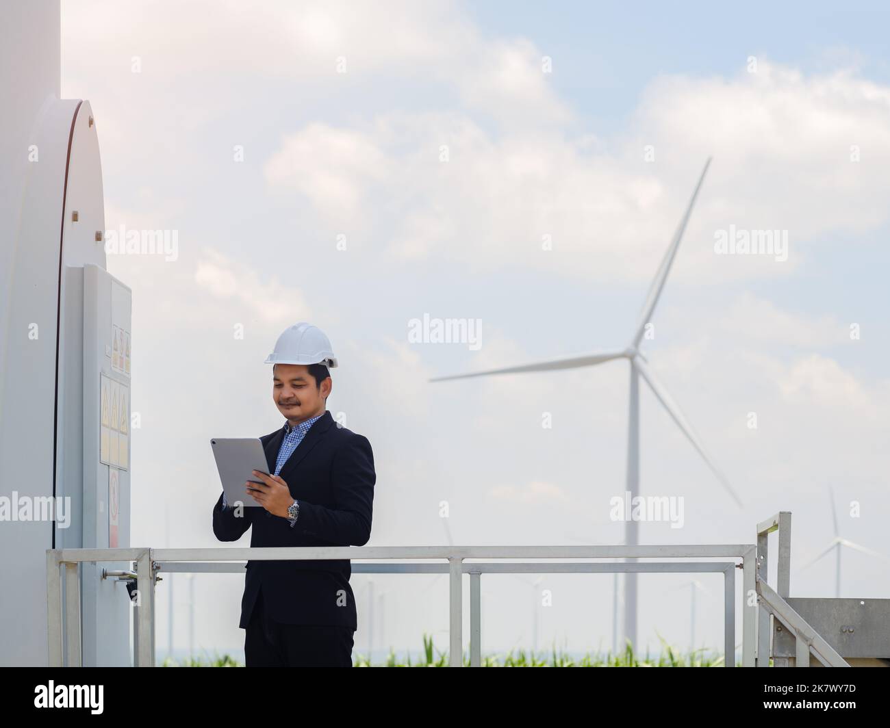 Asian engineer in a suit is using a tablet to control and monitor the ...