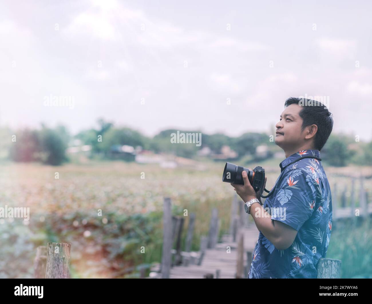 Asian traveler man holding the camera and standing on the old bridge ...