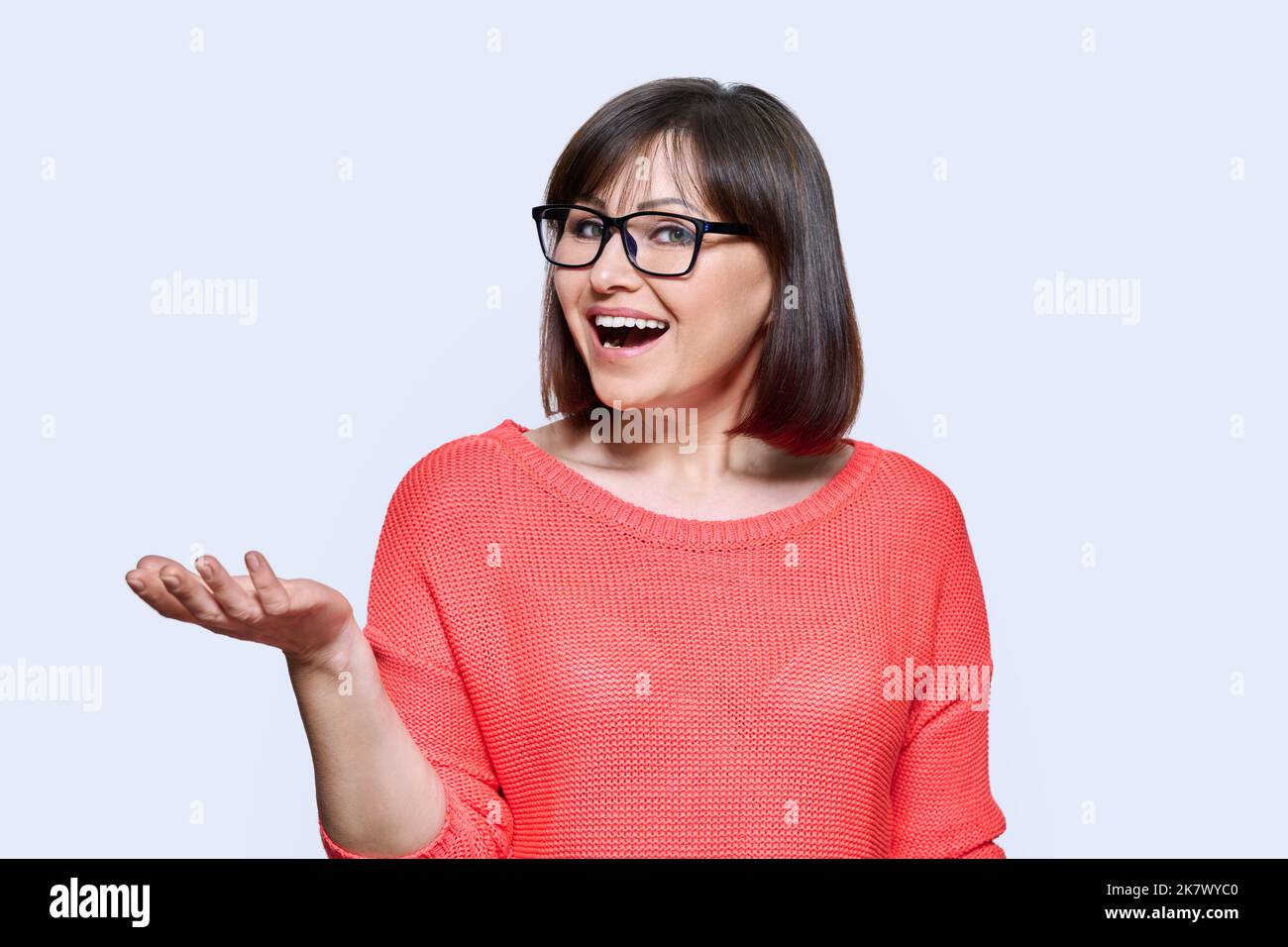 Talking gesturing woman looking at camera on light studio background ...