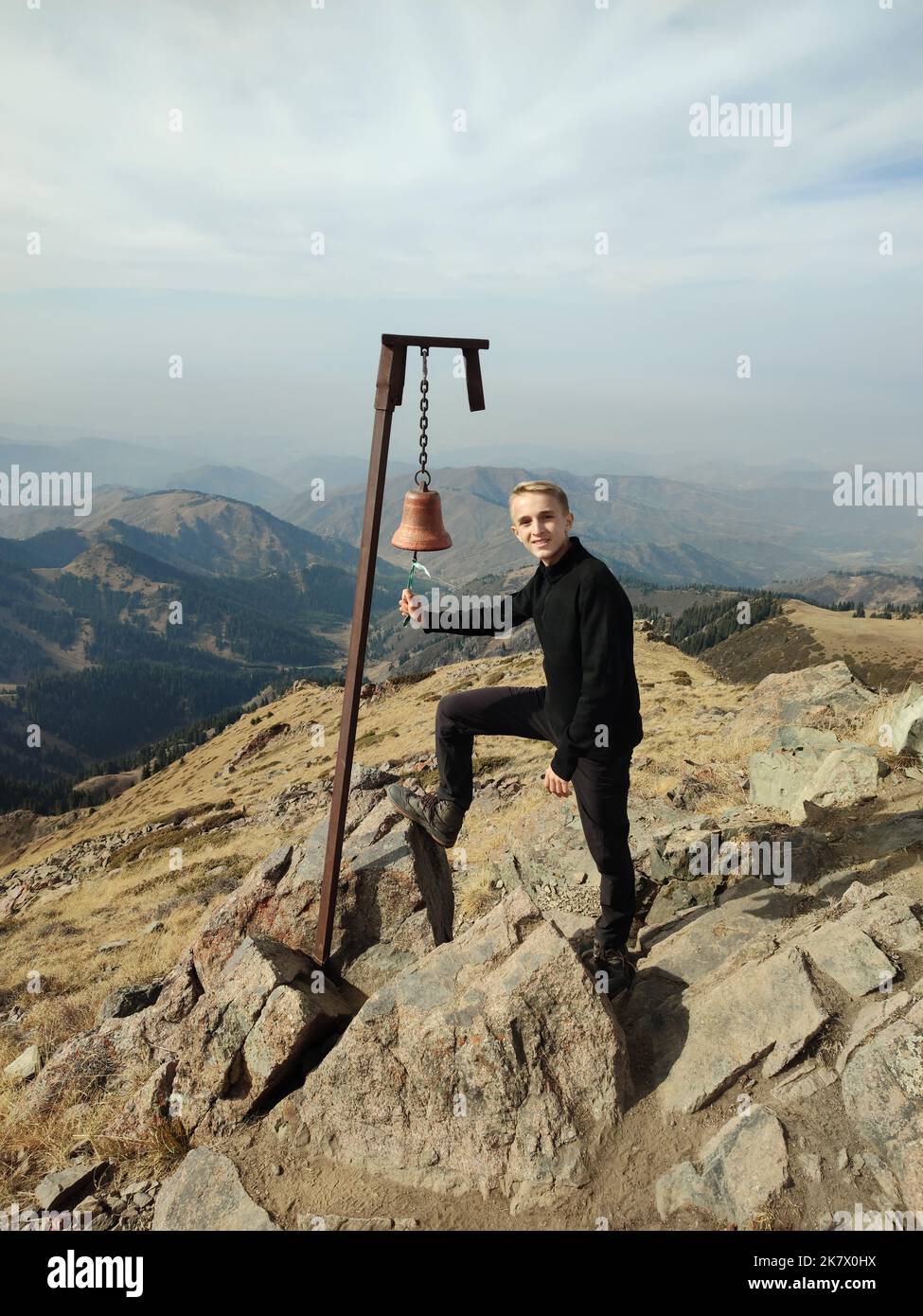 Young man traveler rings bell at the top of mountain Stock Photo - Alamy