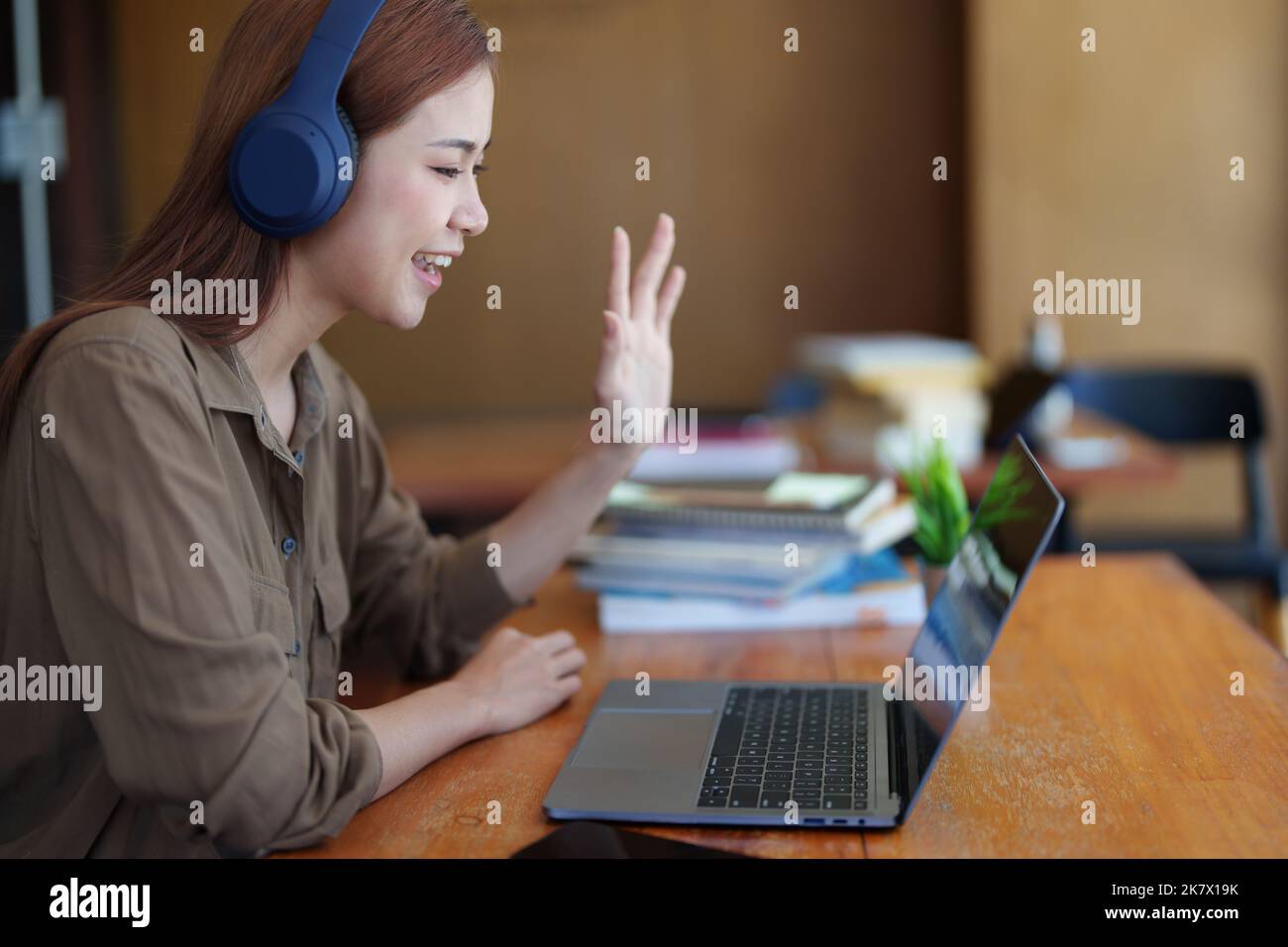 Portrait of a smiling Asian teenage girl wearing headphones and using a ...