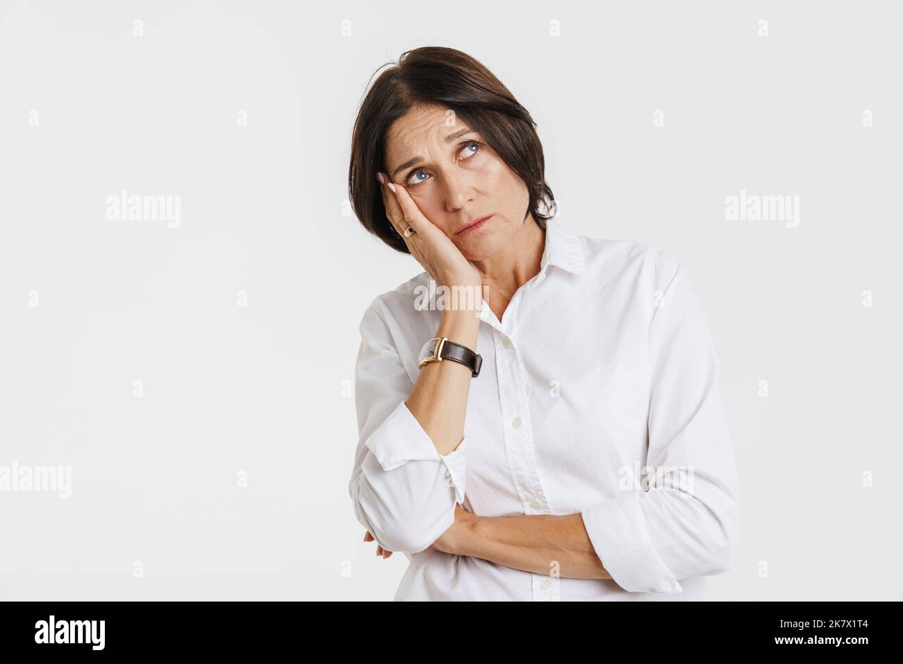 Mature brunette woman frowning while propping her head isolated over ...