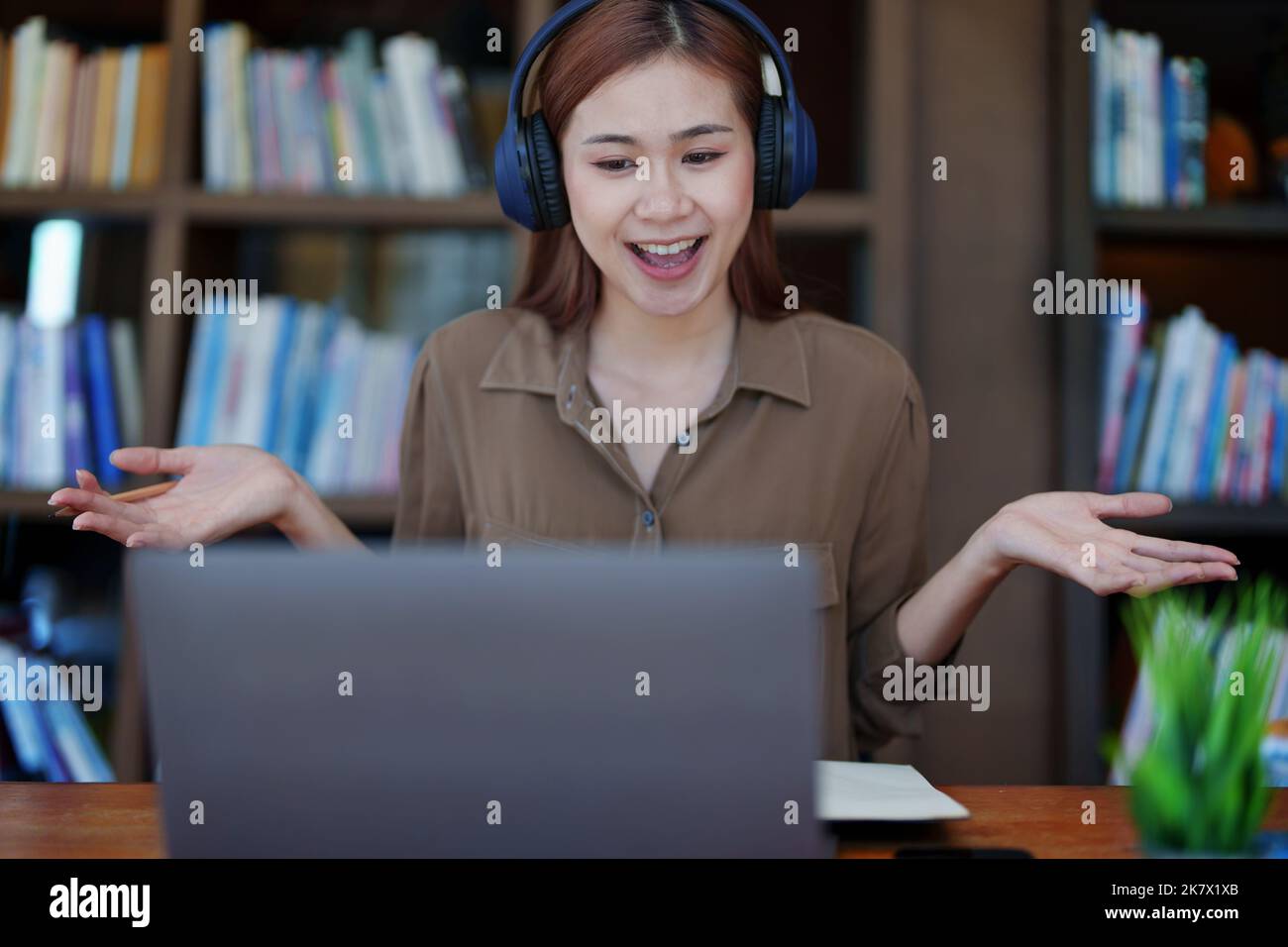 Portrait of a smiling Asian teenage girl wearing headphones and using a ...