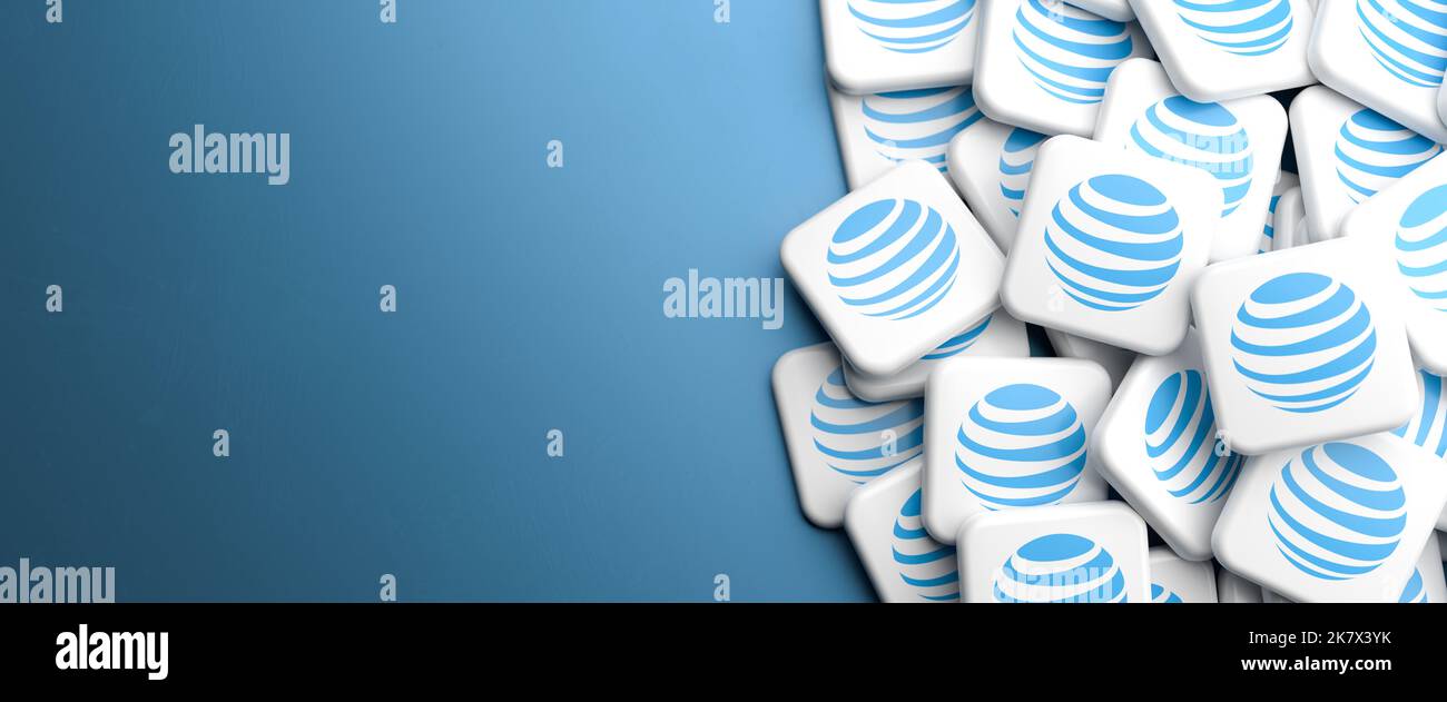 Logos of the telecommunications company AT&T on a heap on a table. Copy ...