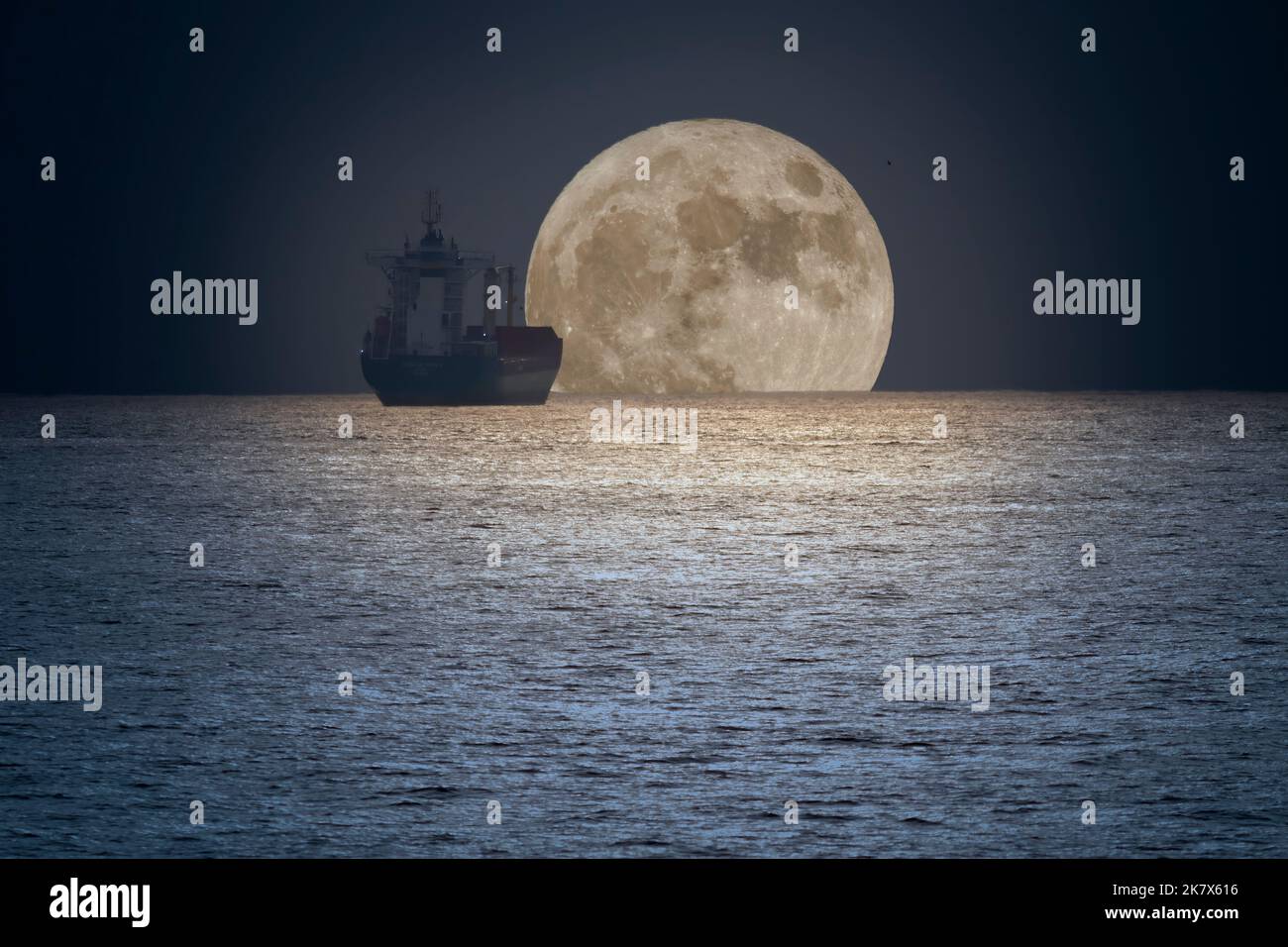 Commercial ship on the horizon in a full moon night Stock Photo - Alamy