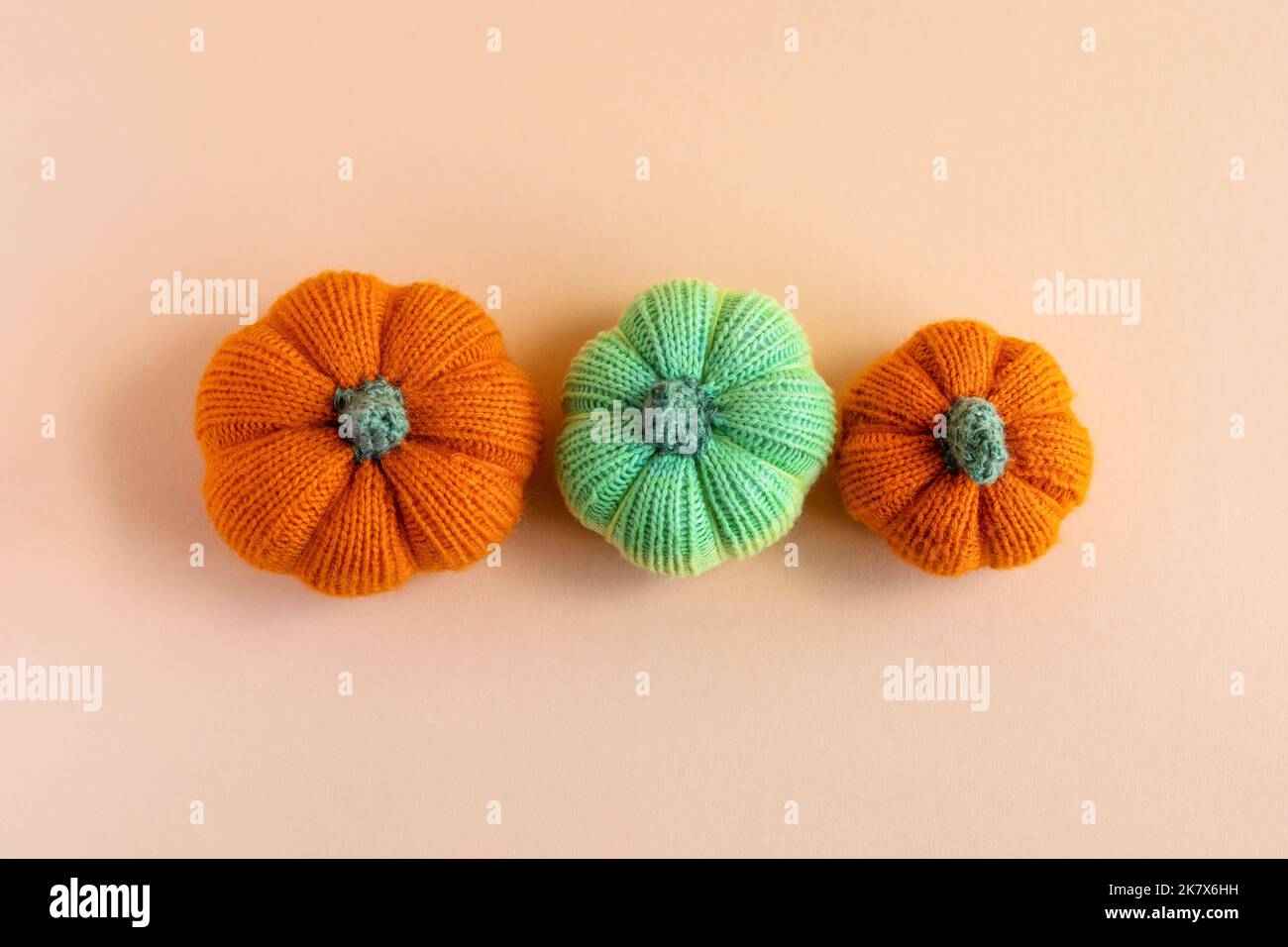Knitted orange and green pumpkins on an orange background, autumn ...