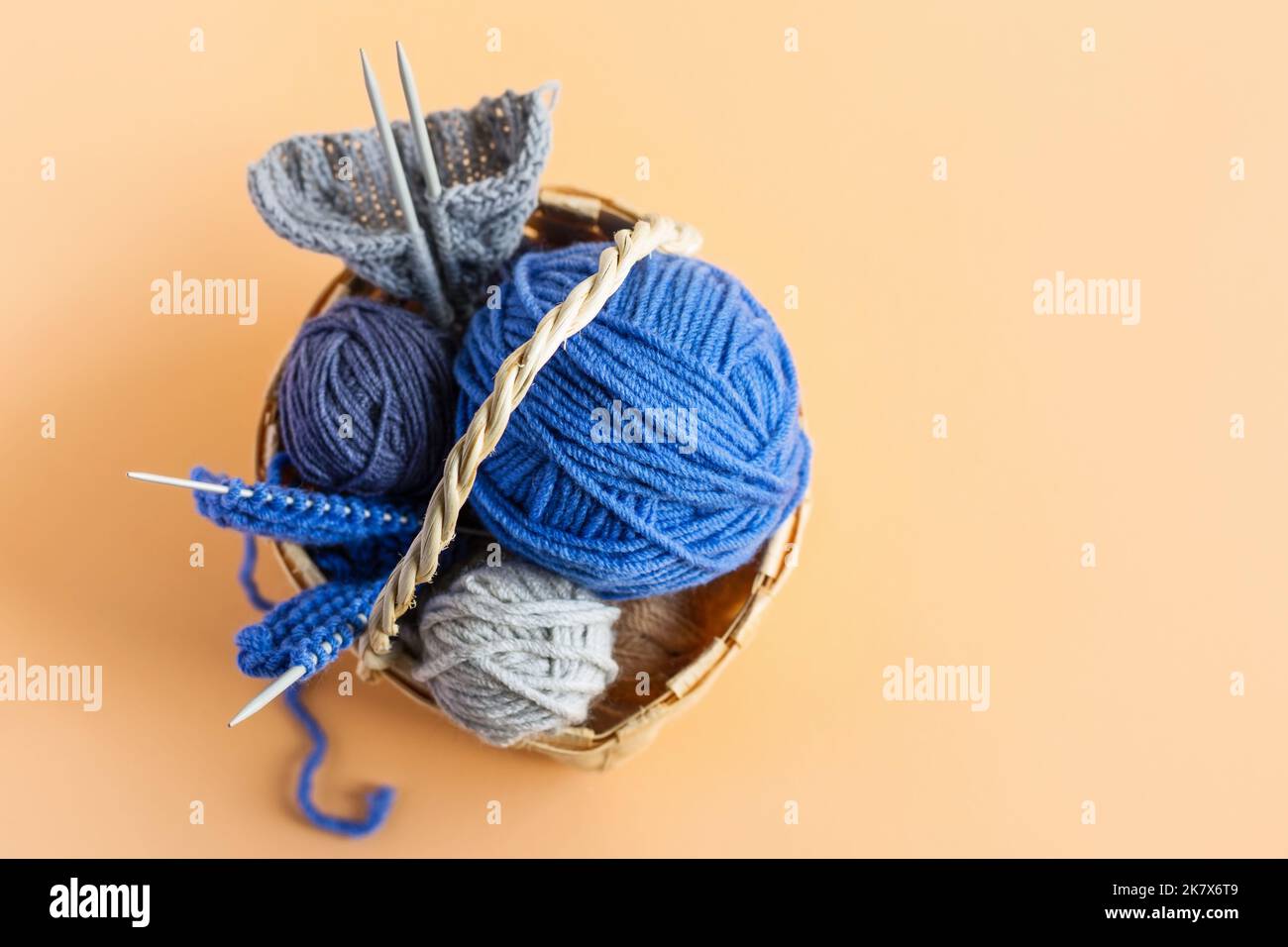 Blue balls of knitting threads on a orange background in a basket with ...