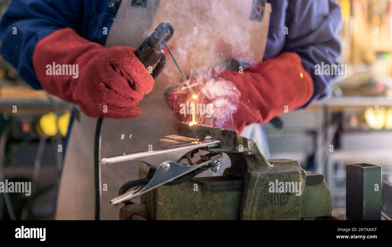A man welder with safety helmet working with arc welding machine in the ...