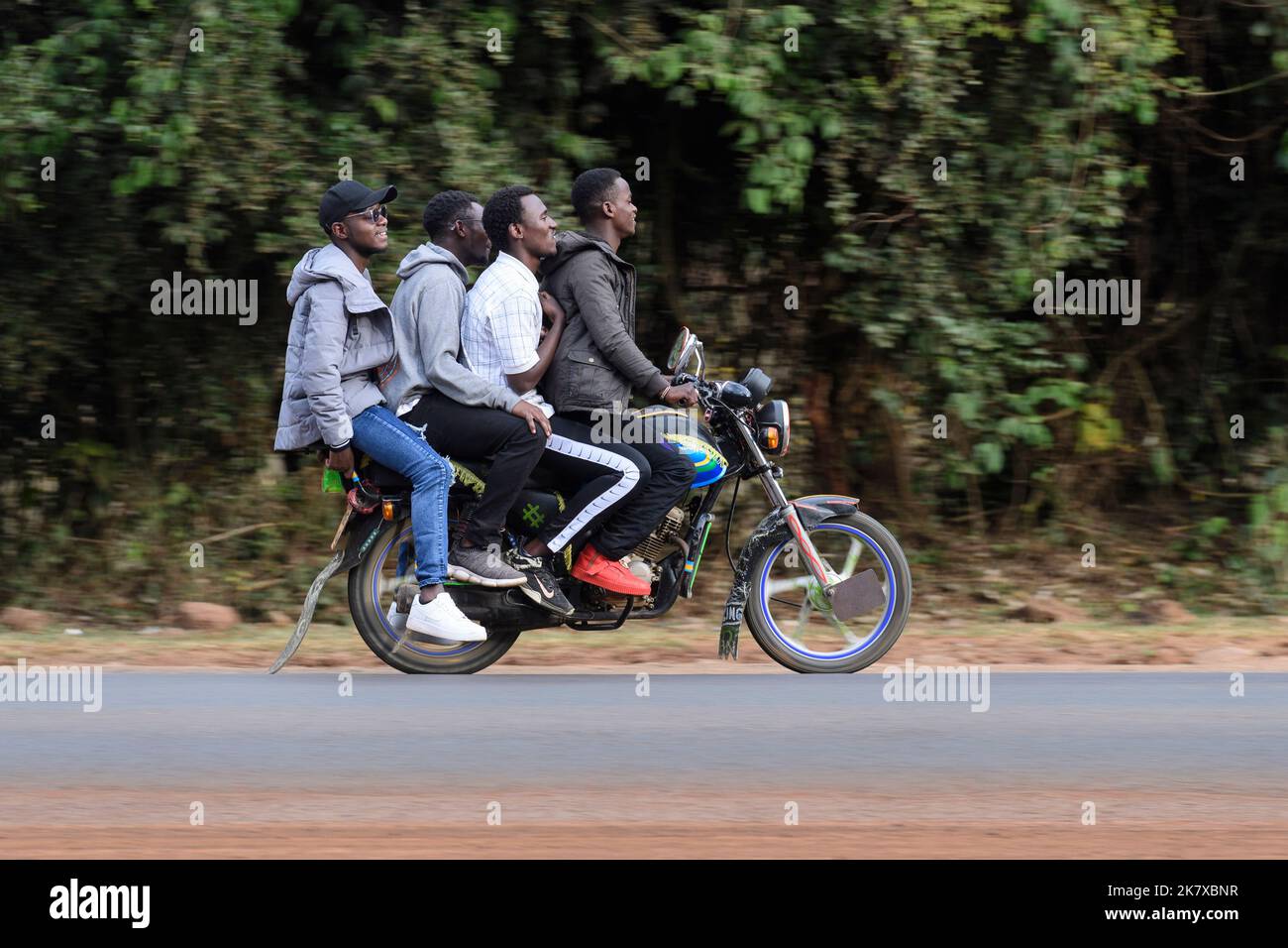 Three pillion passengers riding on motorcycle taxis, know as a Boda ...