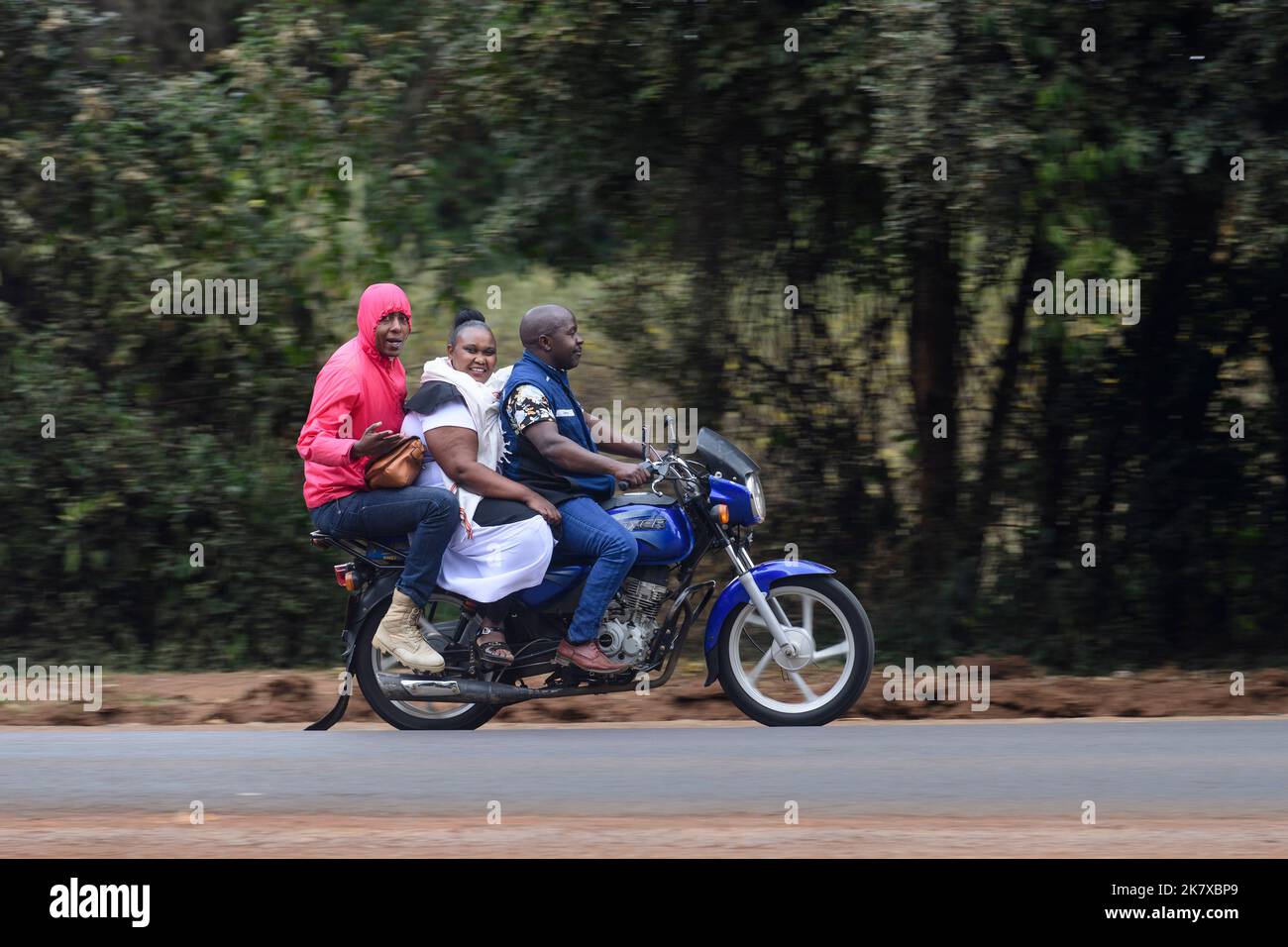 Two pillion passengers riding on motorcycle taxis, know as a Boda boda, in East Africa. Boda ...