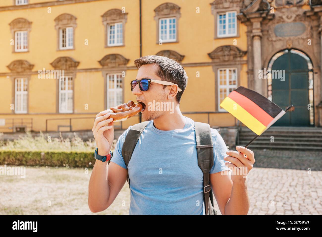 A male tourist with german flag eating pretzel on the background of an ...