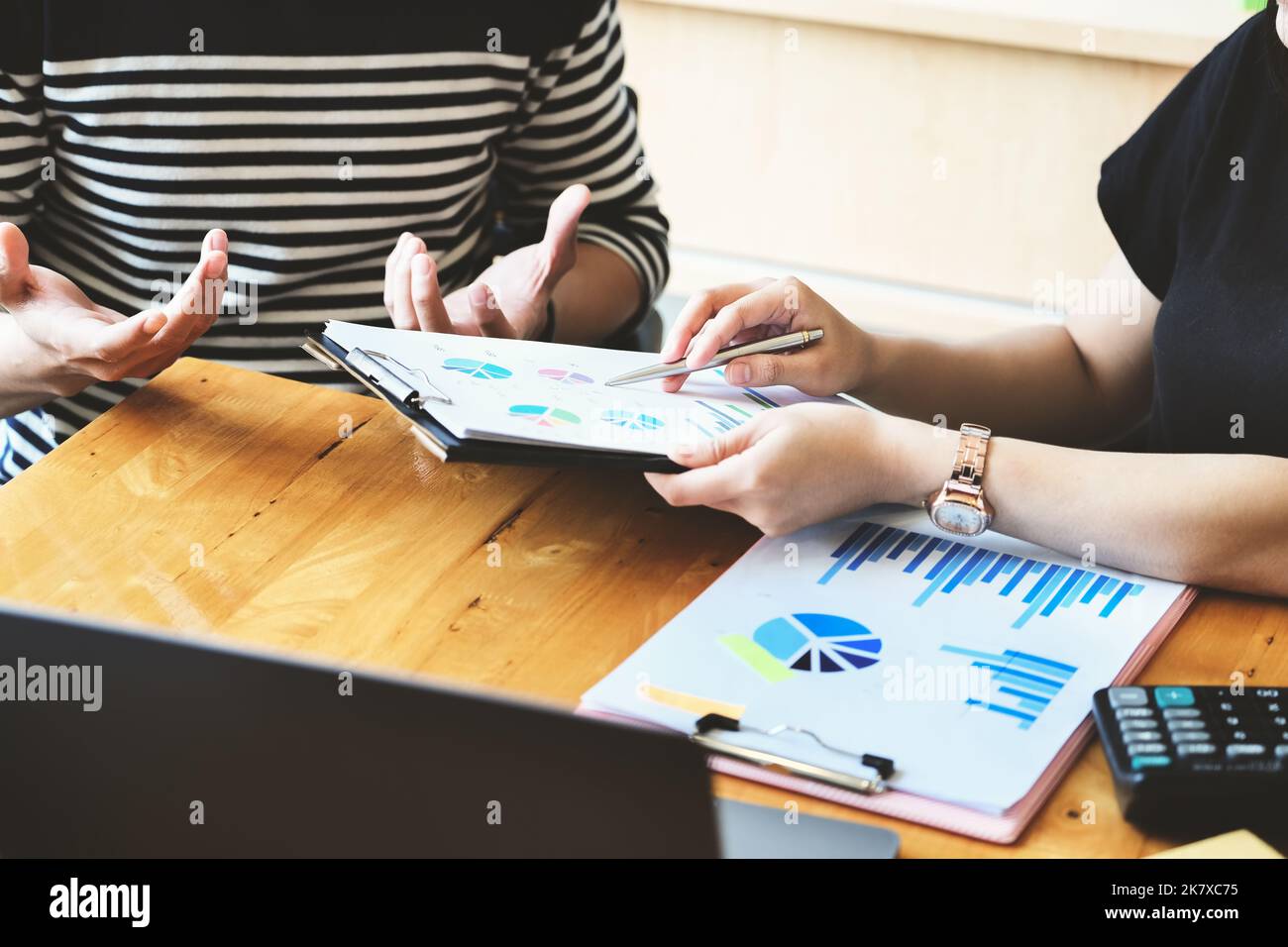 focus hand holding pen point to chart document with business woman and ...