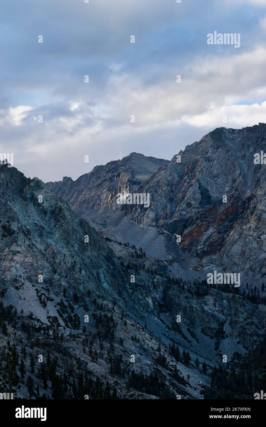 Vertical view of dramatic mountain cliffs descending into a valley with ...