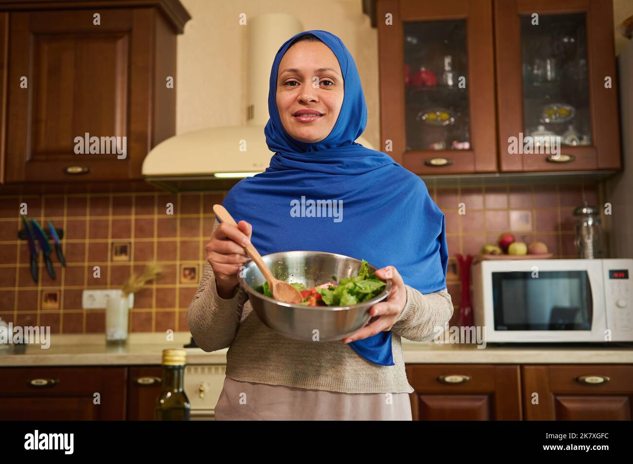 Charming Muslim Arab young woman in hijab, holds a bowl with healthy ...