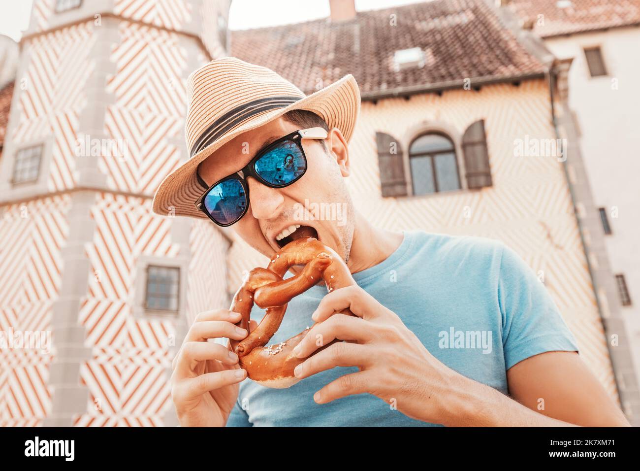 Happy male tourist eating delicious pretzel snack on the background of ...