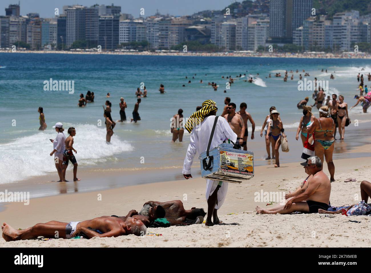 Street food vendor walking at Copacabana beach. Man walks selling goods ...