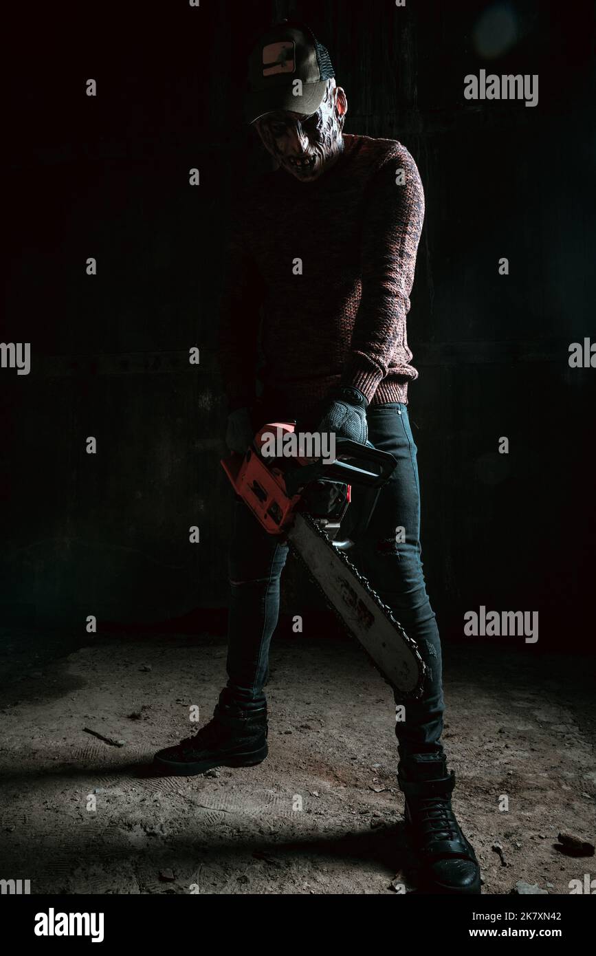 Evil in mask with chainsaw, horror Halloween scene in dark room Stock ...