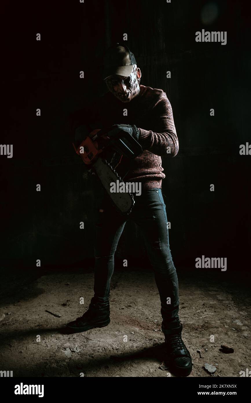 Evil in mask with chainsaw, horror Halloween scene in dark room Stock ...