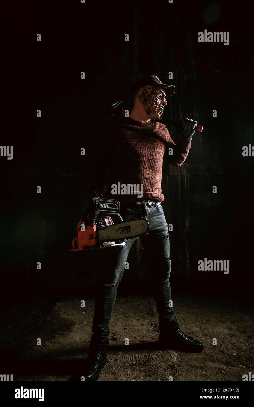 Evil in mask with chainsaw, horror Halloween scene in dark room Stock ...