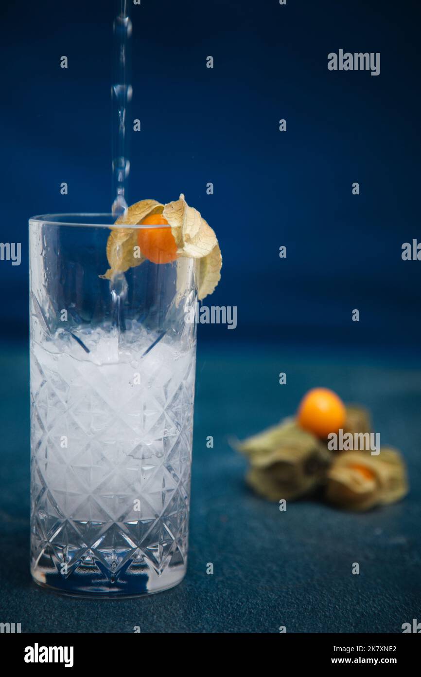 Cocktail being poured with Physalis alkekengi in the background and ...