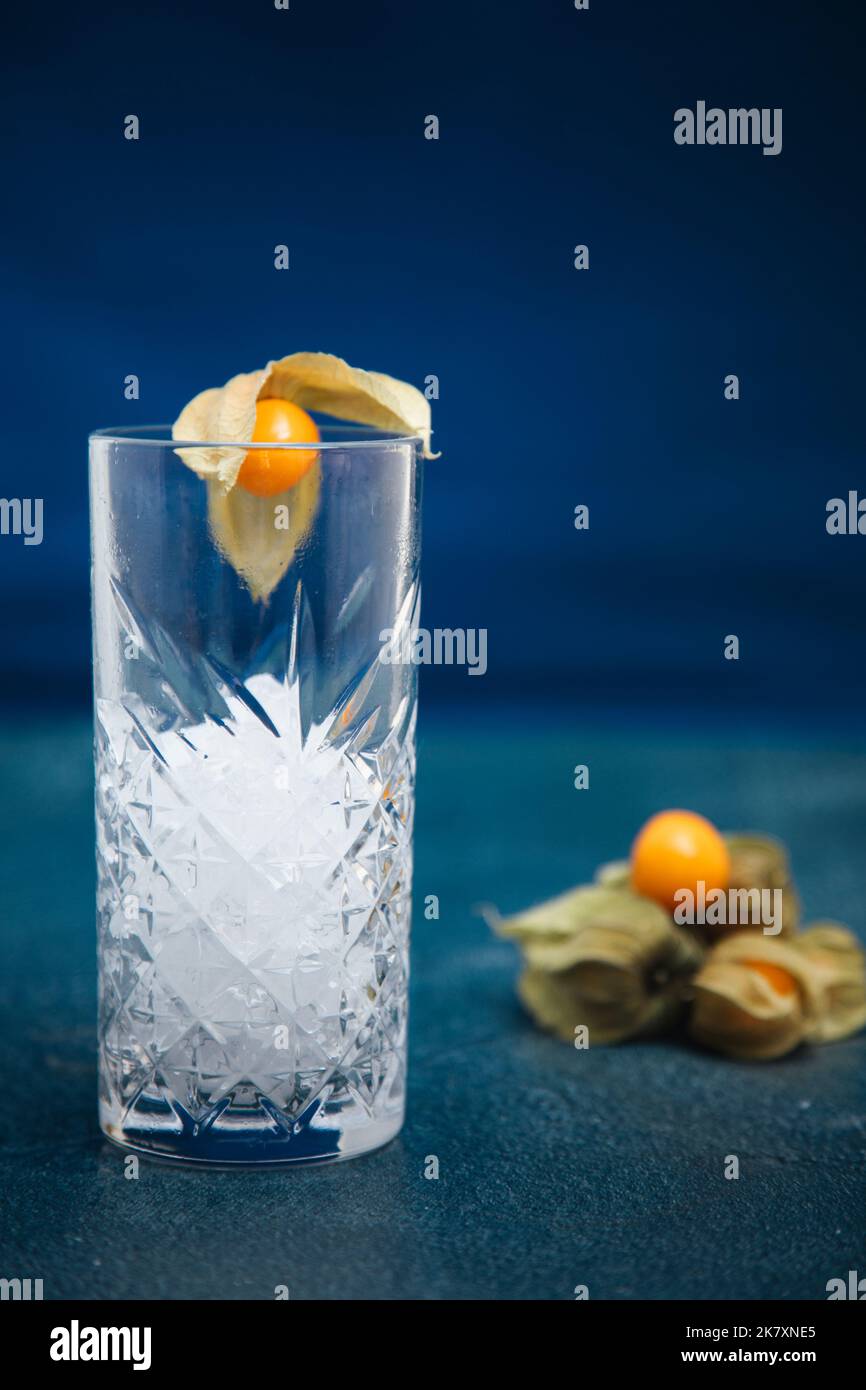 Cocktail being poured with Physalis alkekengi in the background and ...