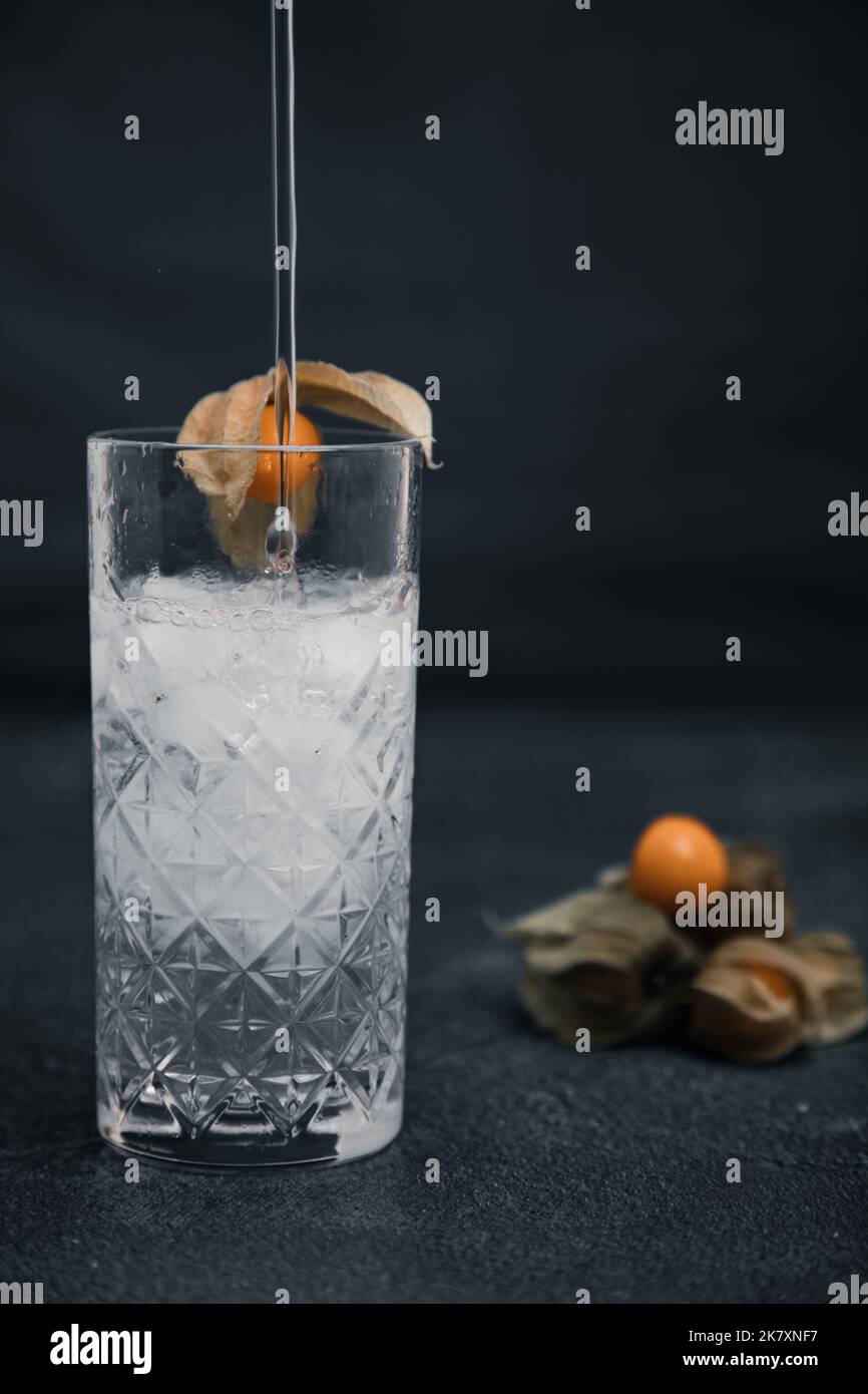 Cocktail being poured with Physalis alkekengi in the background and ...