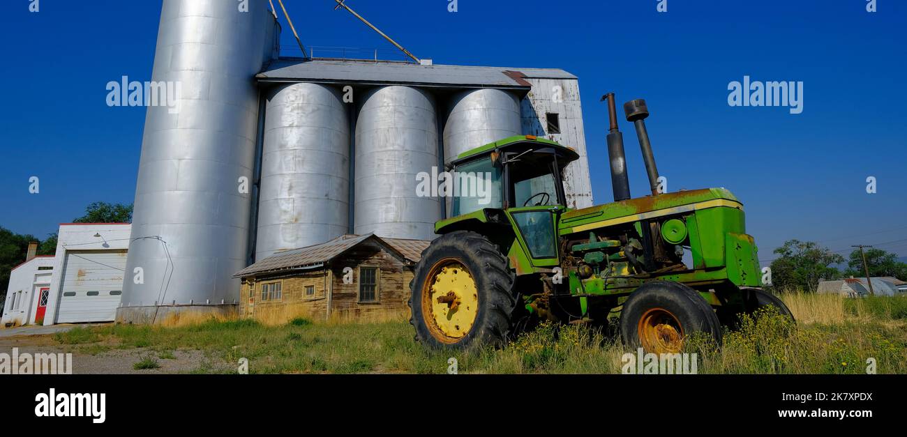 Grain elevator and tall storage silos with old green tractor Stock ...