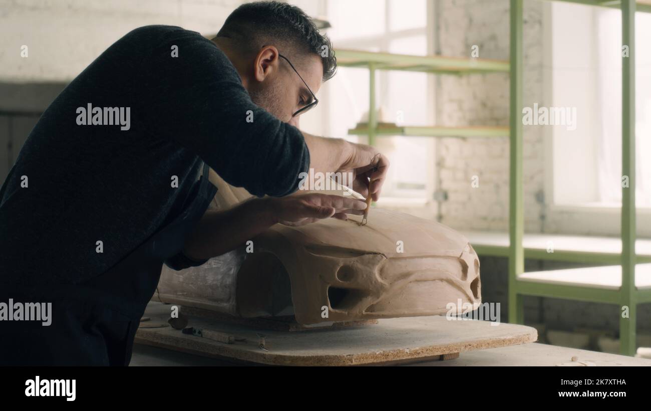 Senior car designer sculpting a electric car model prototype. Uses ...
